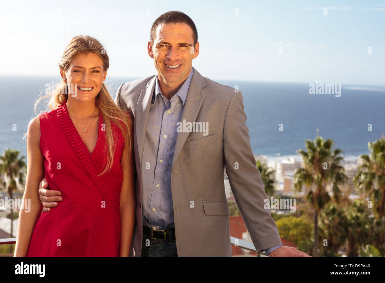 Couple smiling at camera on balcony Stock Photo - Alamy