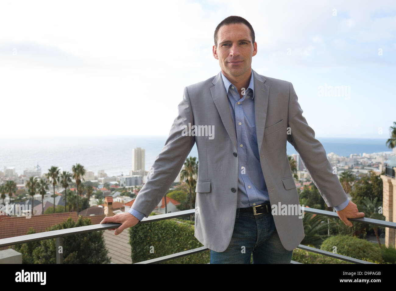 Handsome man leaning on balcony Stock Photo - Alamy