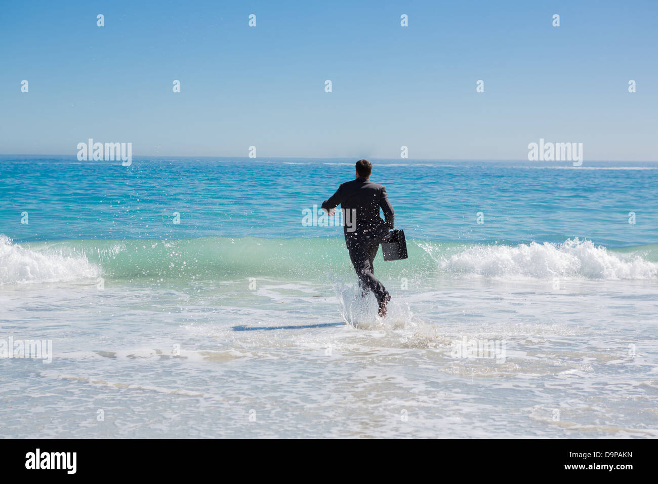 Businessman running into the ocean Stock Photo - Alamy