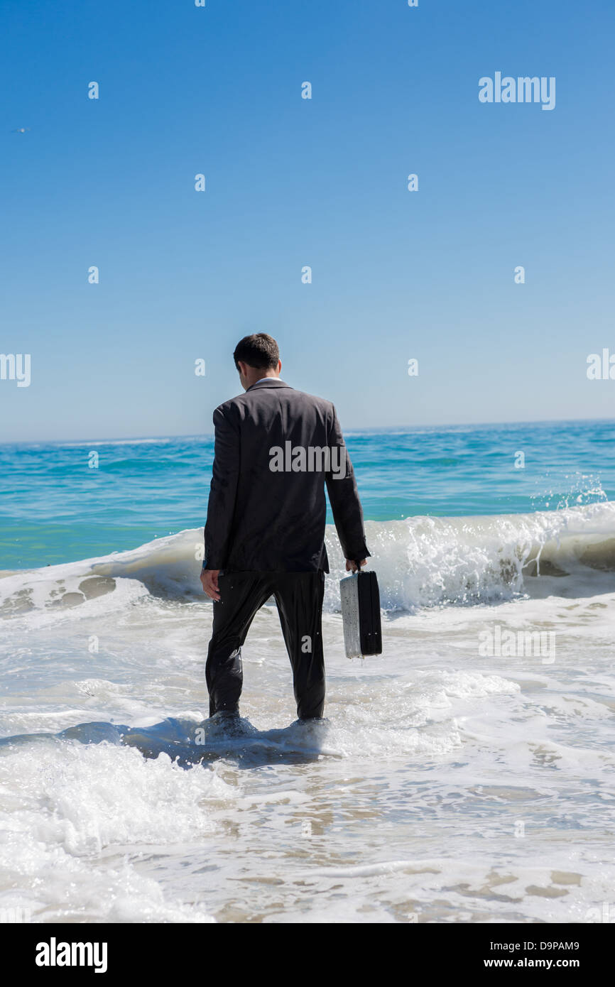 Businessman walking into the sea Stock Photo - Alamy