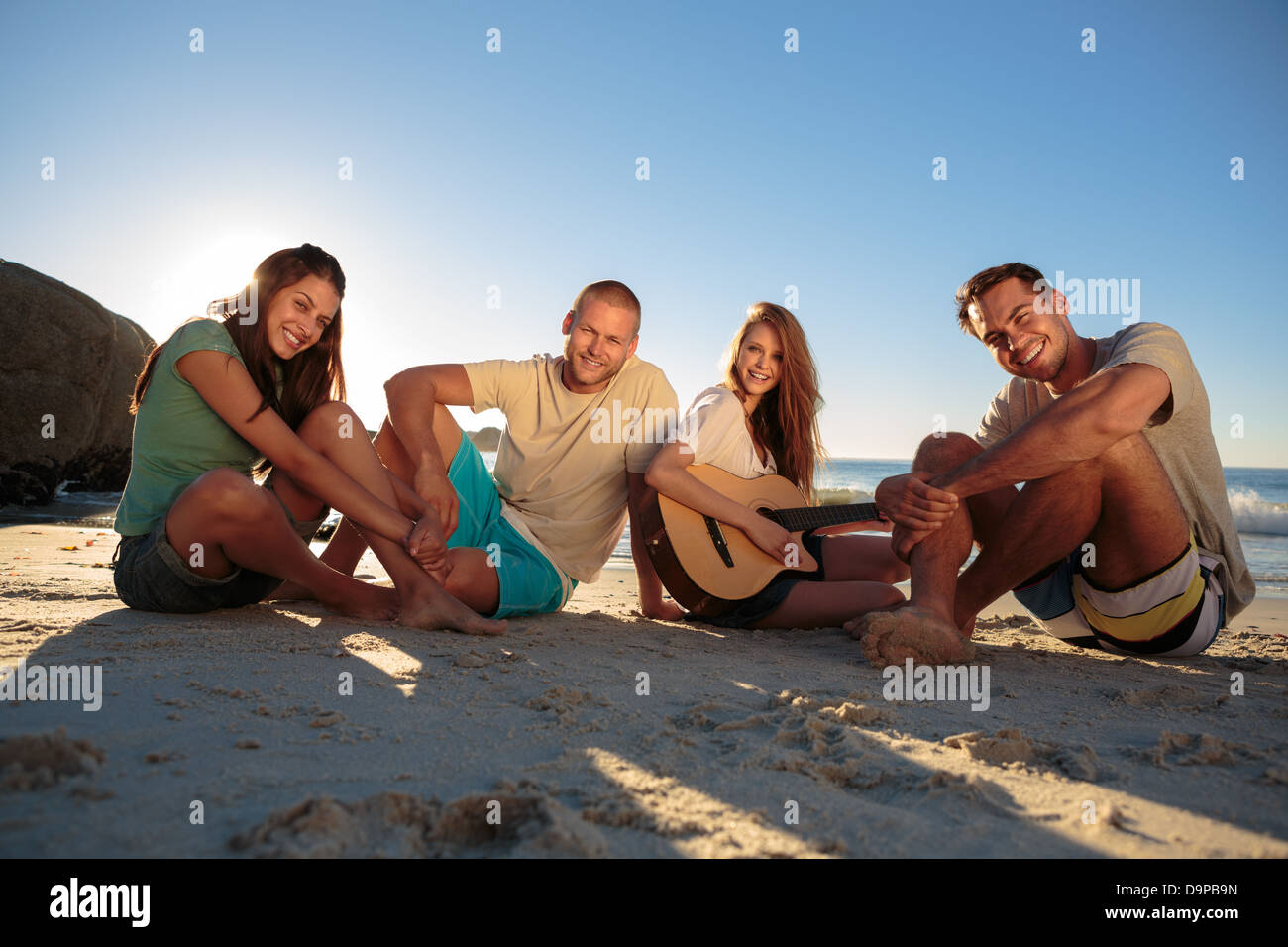 Group of friends sitting on the beach Stock Photo - Alamy