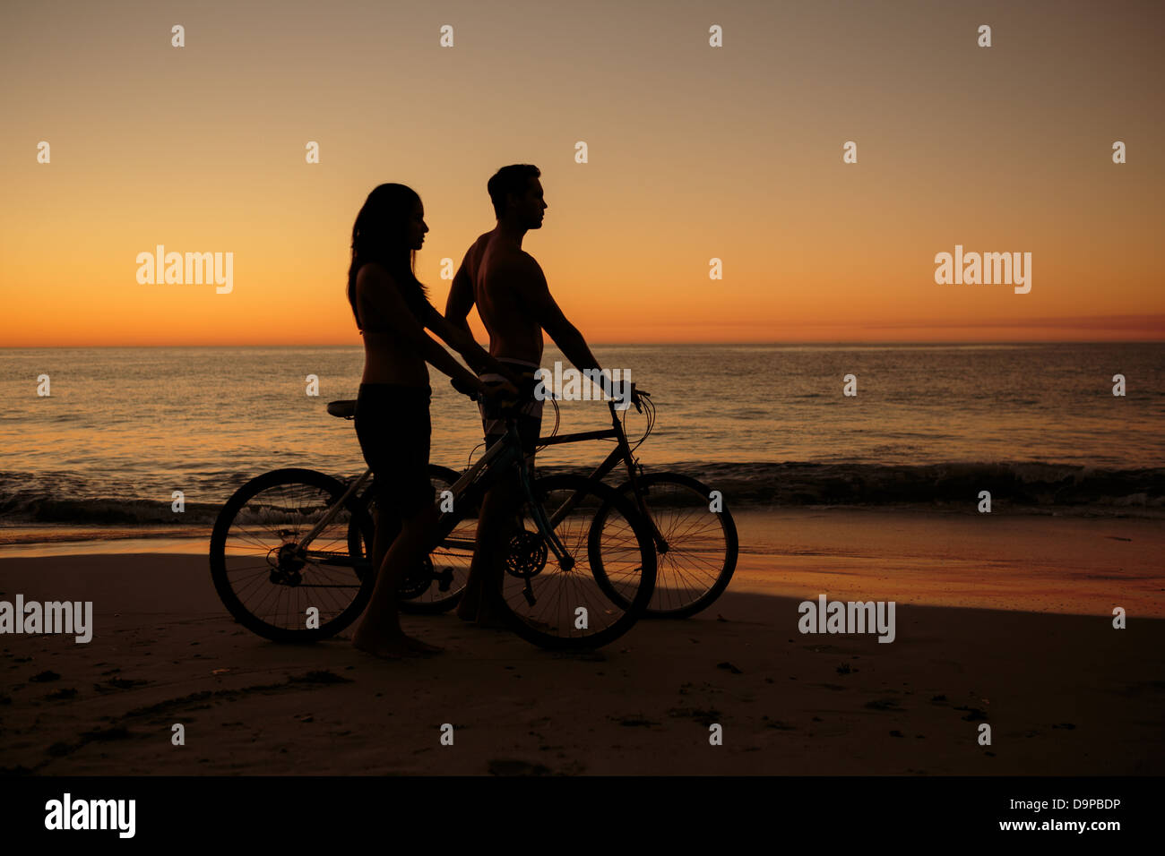 Couple biking together on the beach Stock Photo - Alamy