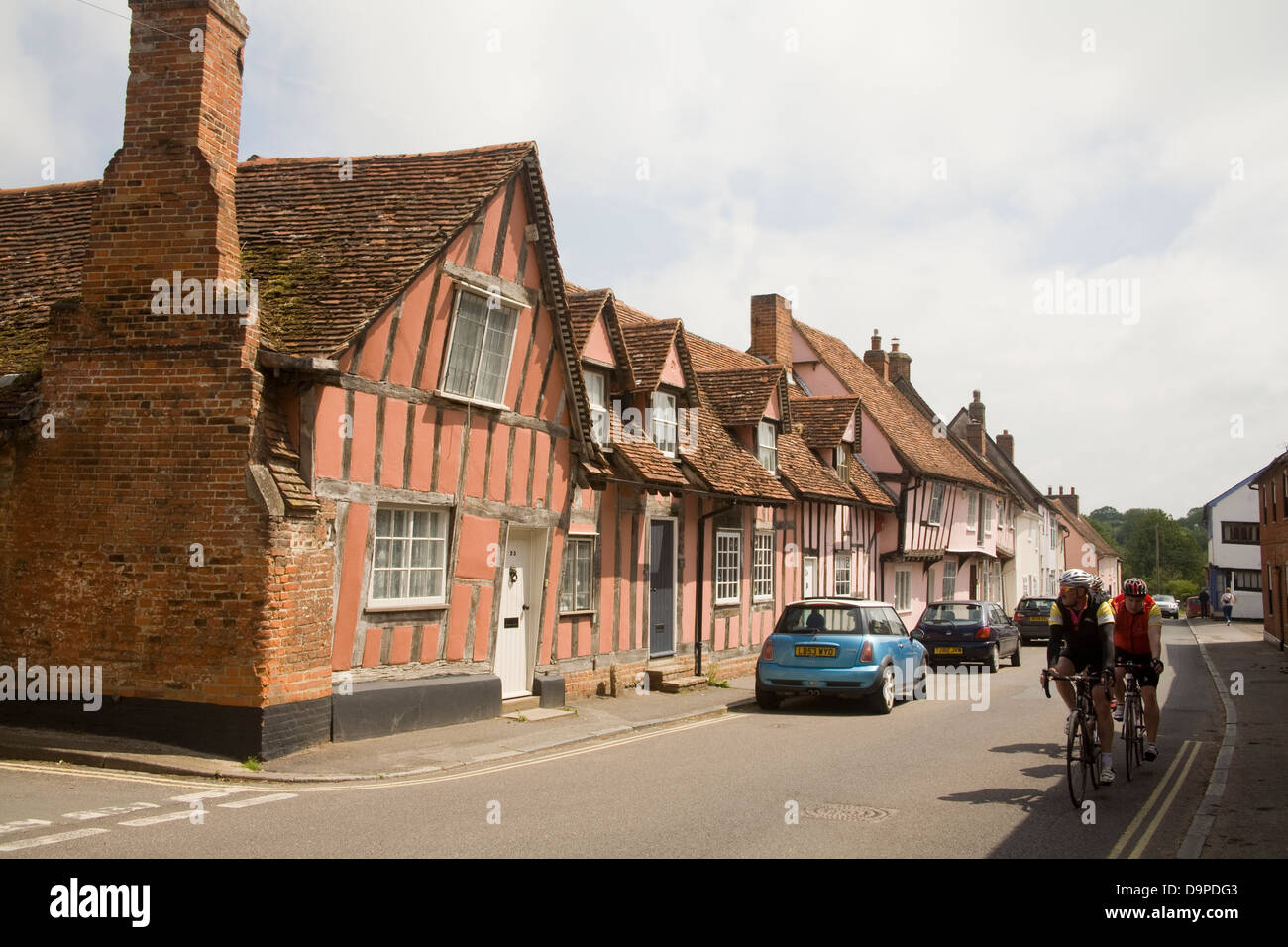 Lavenham Suffolk East Anglia England Two cyclists cycling past terrace ...
