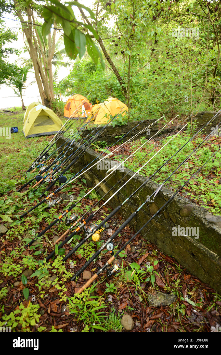 campsite, tents, fishing poles with reels lined up and ocean in ...