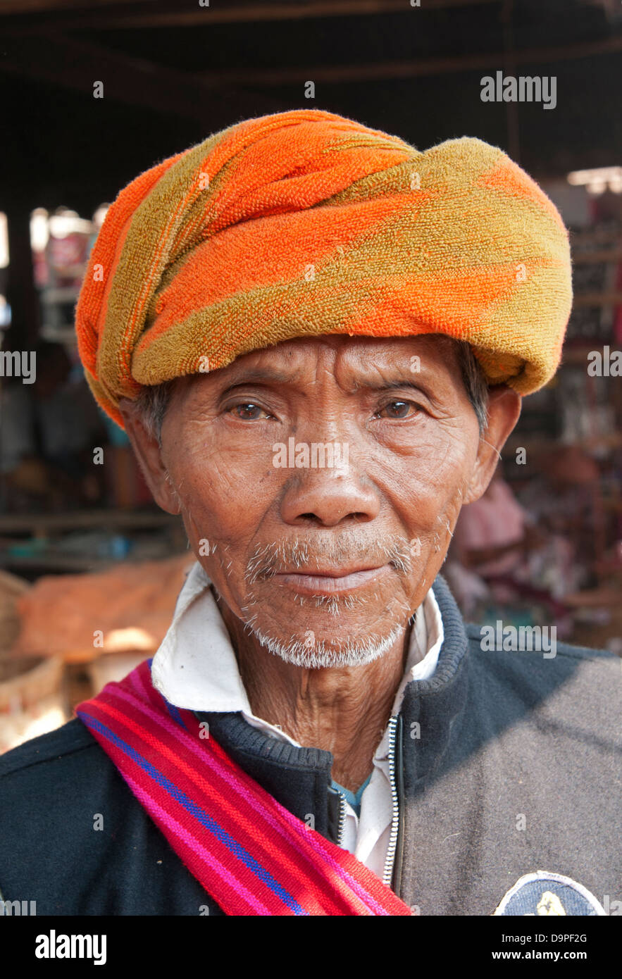 Old Pa-O man wearing orange and yellow headdress stares at the camera ...