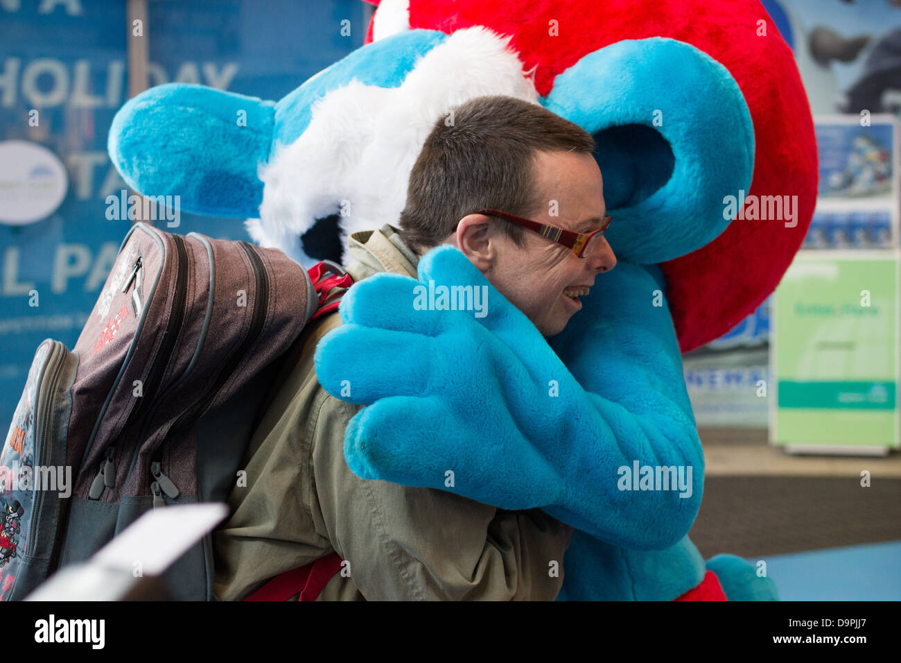 A person wearing a Papa Smurf costume gives a hug to a man with a ...