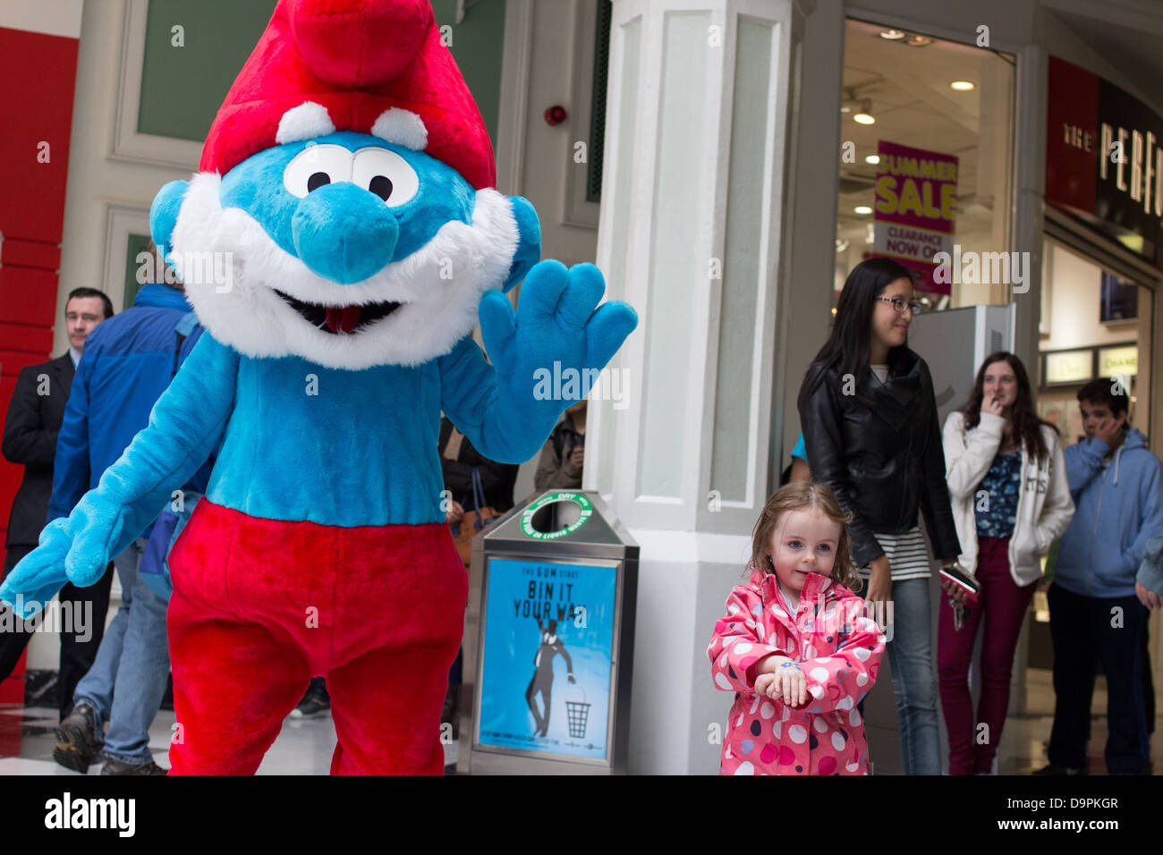 A person wearing a Papa Smurf costume stands beside a little girl Stock ...