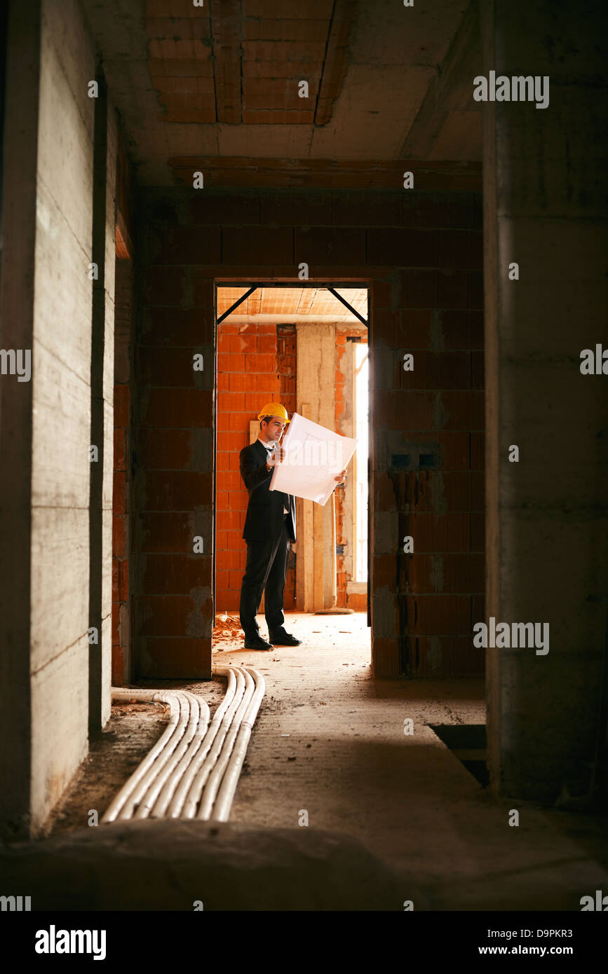 Engineer at work in construction site, standing in apartment building ...