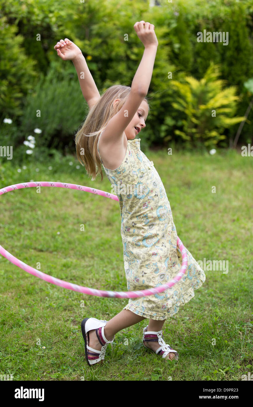 Smiling little girl playing with hula hoop in her garden Stock Photo ...