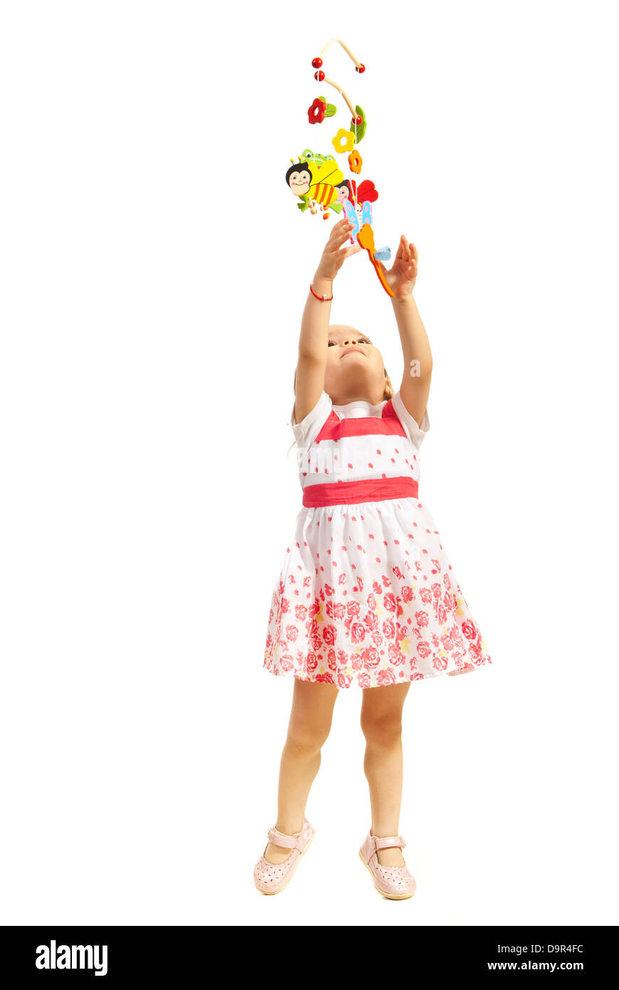 Pretty toddler girl catching toys from baby carousel isolated on white ...