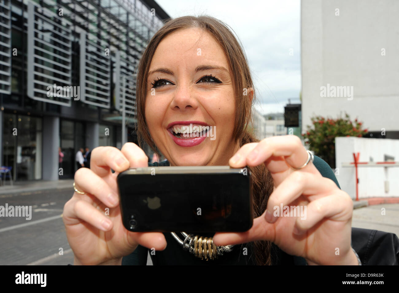 Young woman 20s using an Apple IPhone to take photographs and send ...