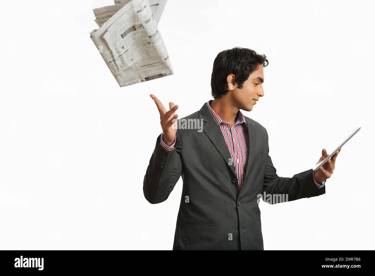 Businessman looking at a digital tablet and throwing newspaper Stock ...