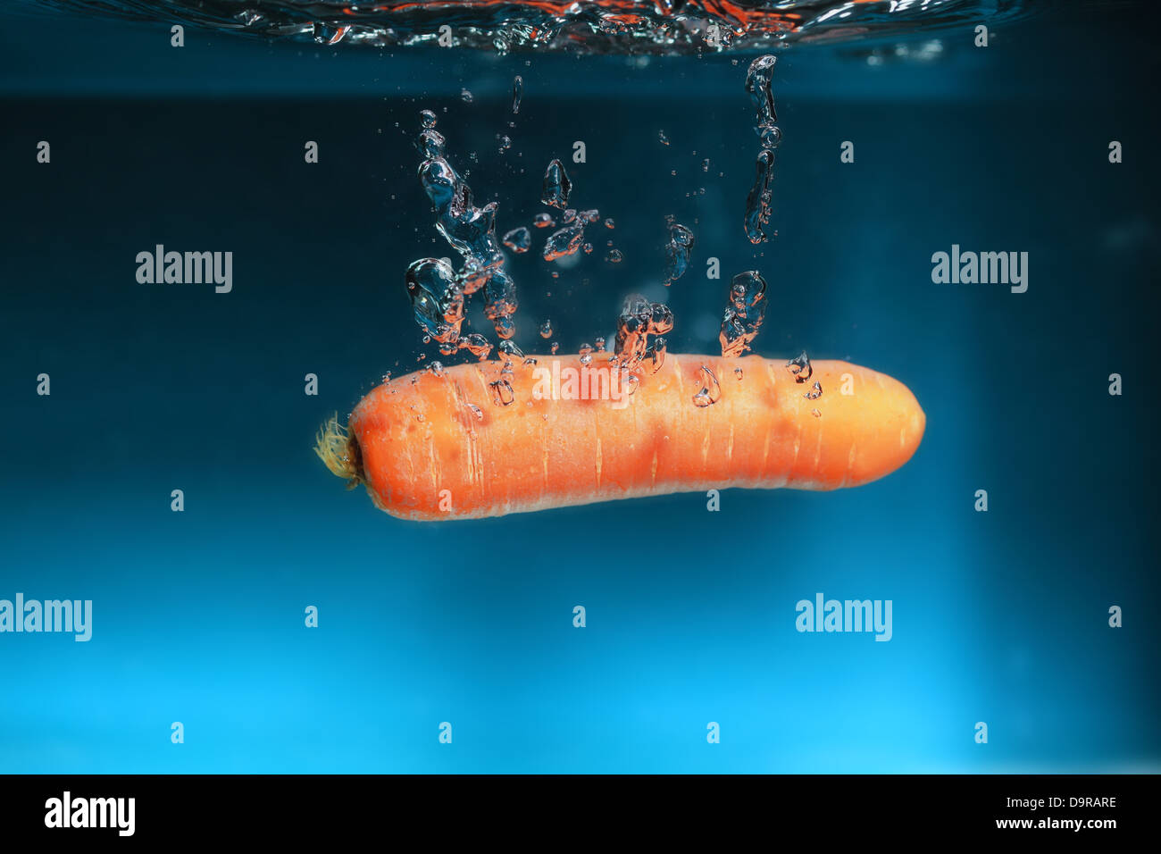 Carrot in the water splash over blue background. Healthy food and ...