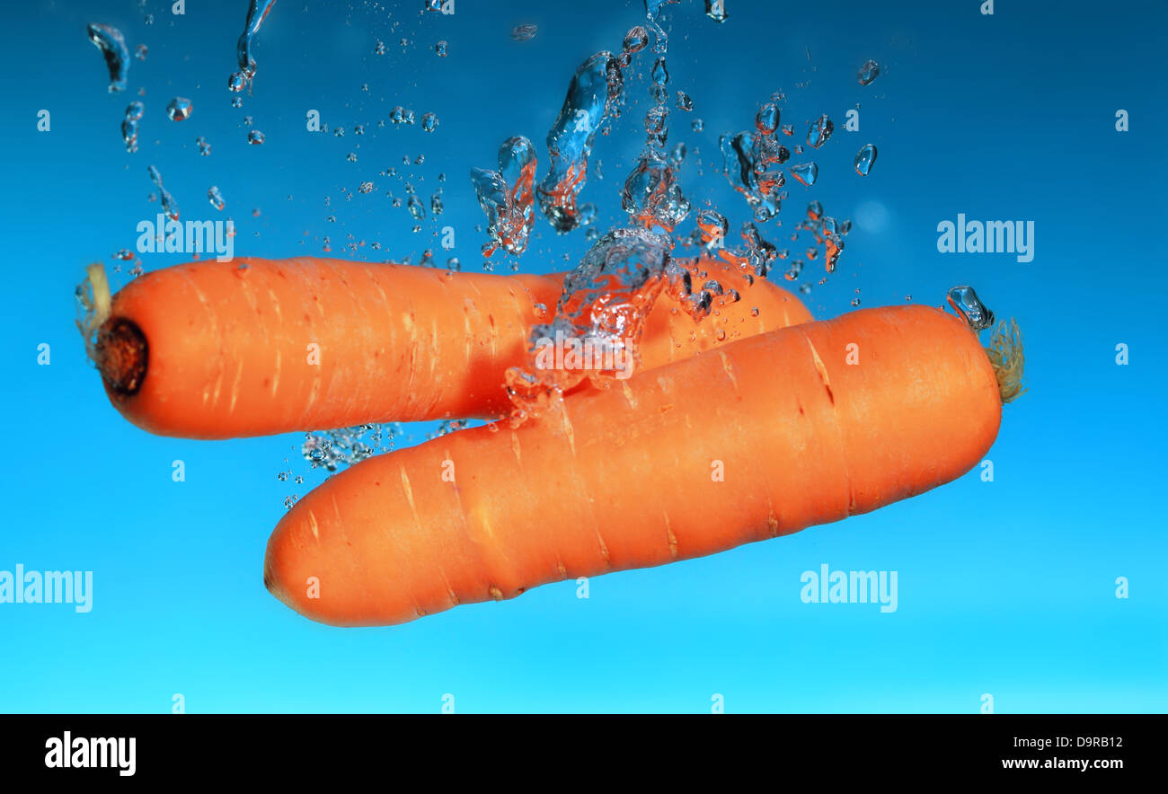 Carrot in the water splash over blue background. Healthy food and ...
