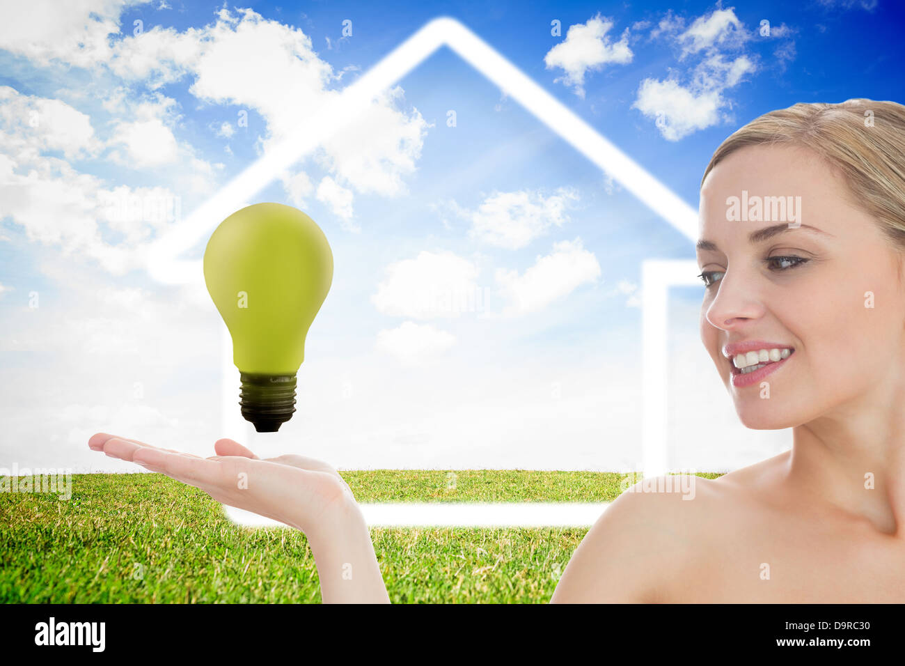 Young woman looking at green light bulb Stock Photo - Alamy