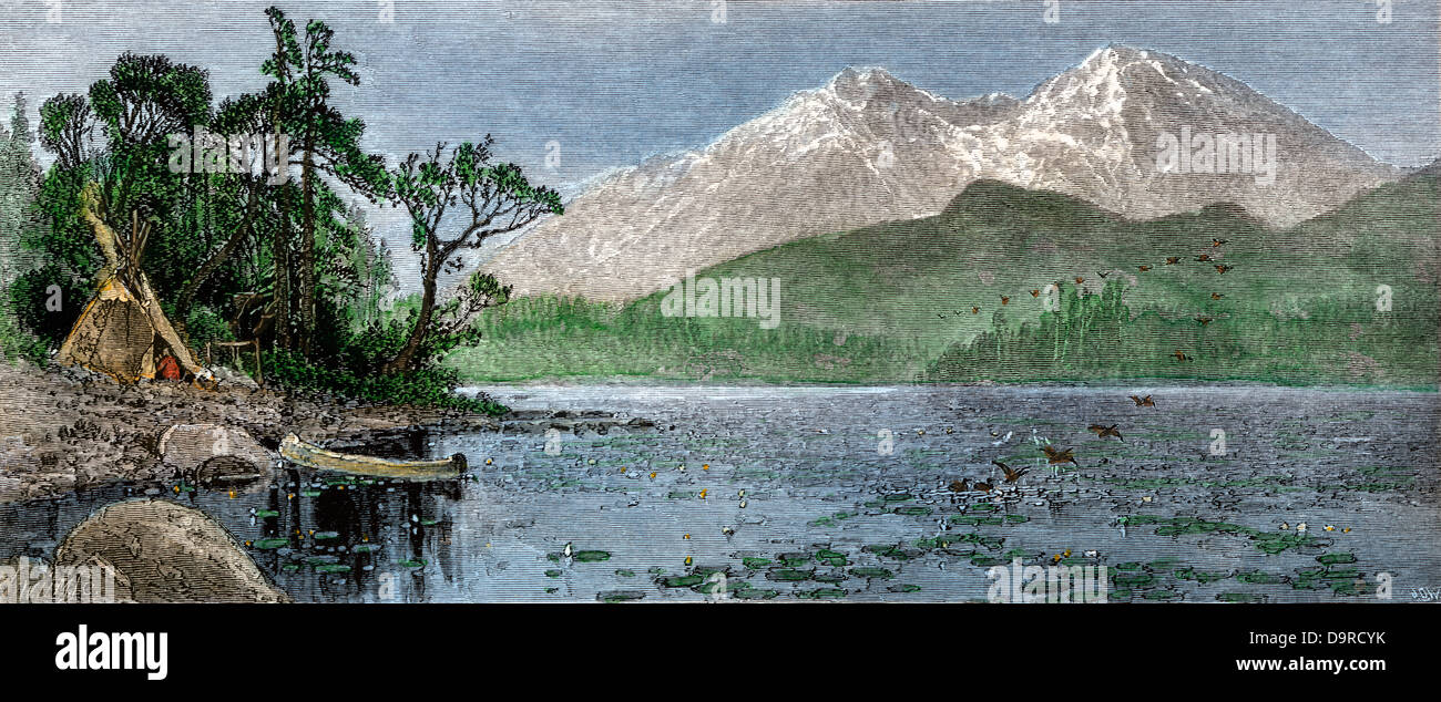 Native American tipi and canoe on the shore of lake beneath Long's Peak ...