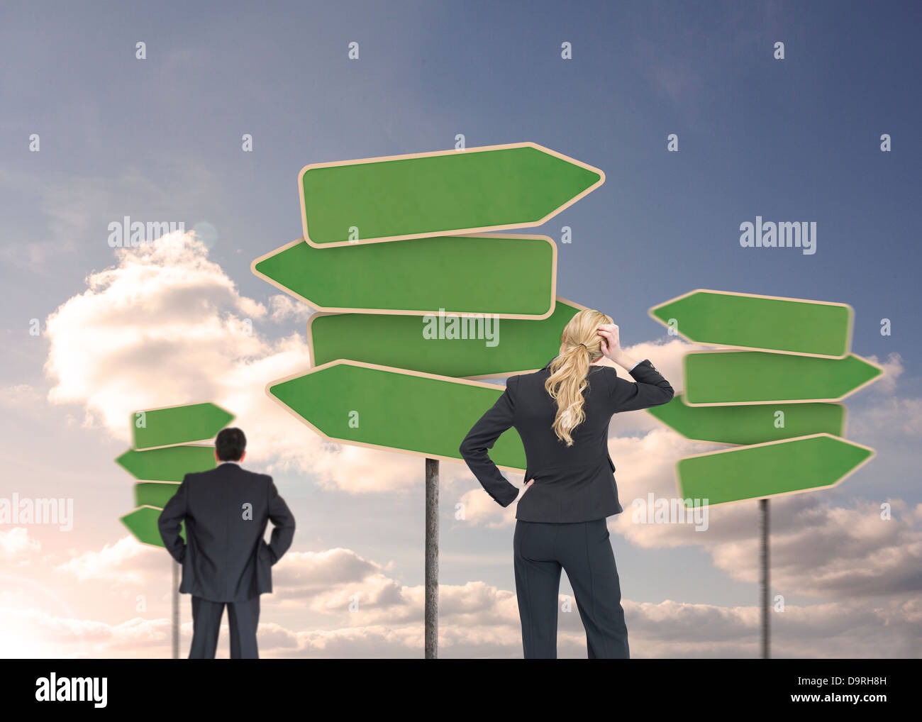 Rear view of businesspeople looking at empty signposts Stock Photo - Alamy