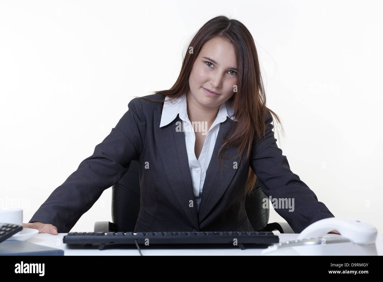 young looking woman at her desk looking at the camera Stock Photo - Alamy