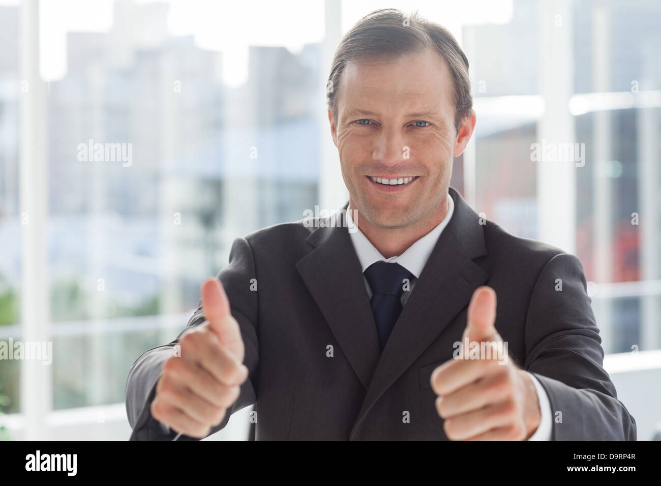 Smiling businessman giving thumbs up Stock Photo - Alamy