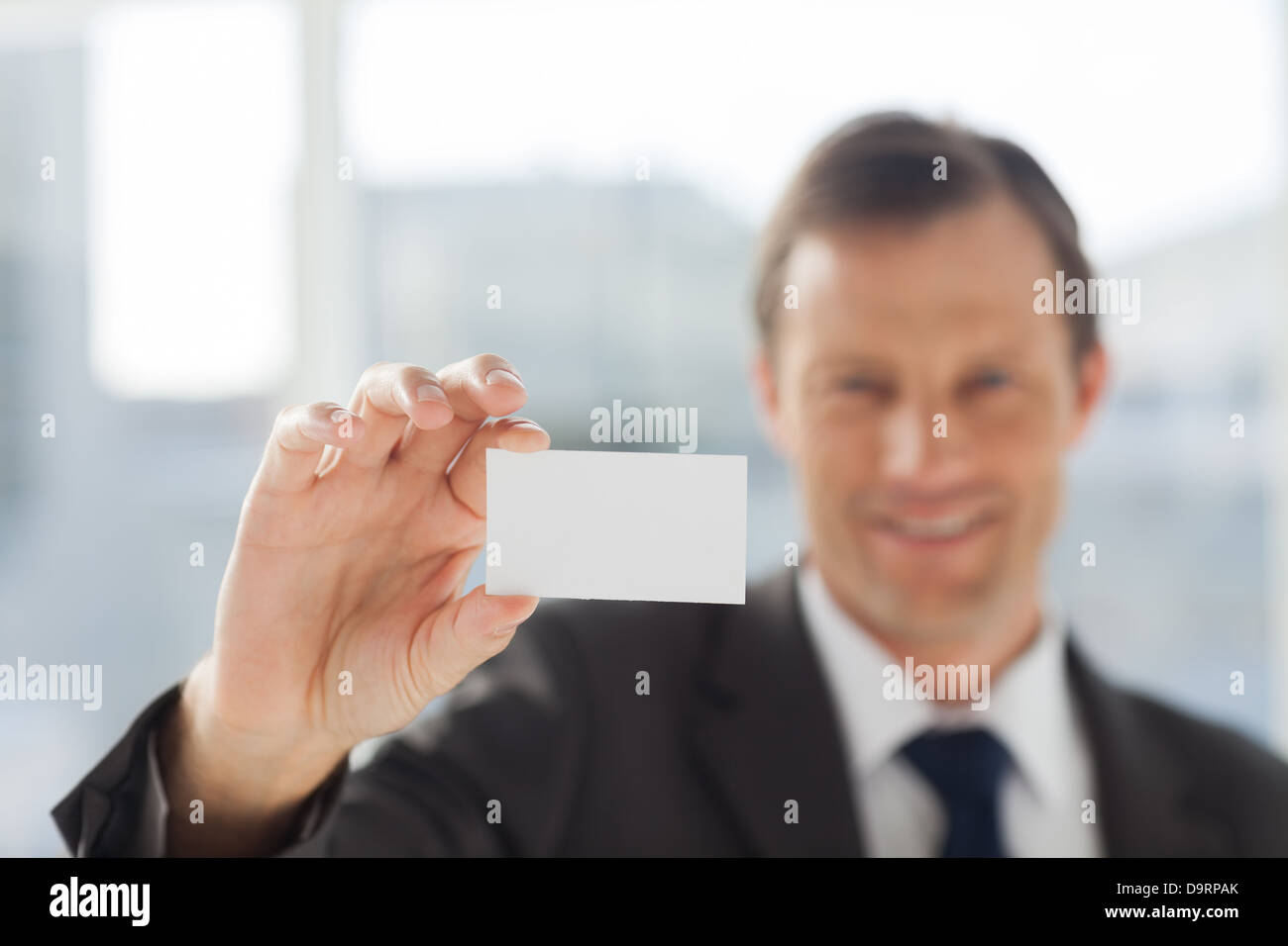 Smiling businessman showing business card Stock Photo - Alamy