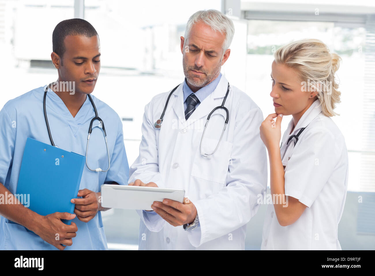 Three doctors using a tablet Stock Photo - Alamy