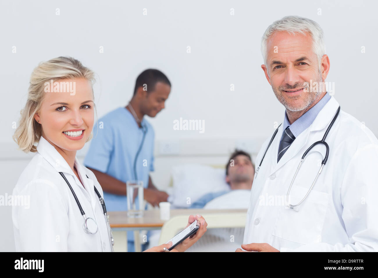 Smiling doctors standing in front of patient Stock Photo - Alamy