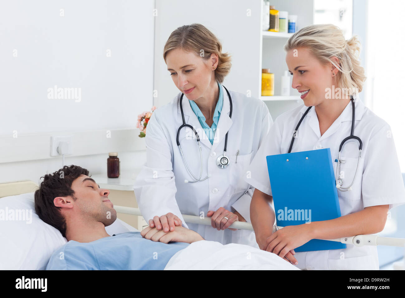 Two women doctors taking care of a patient Stock Photo - Alamy