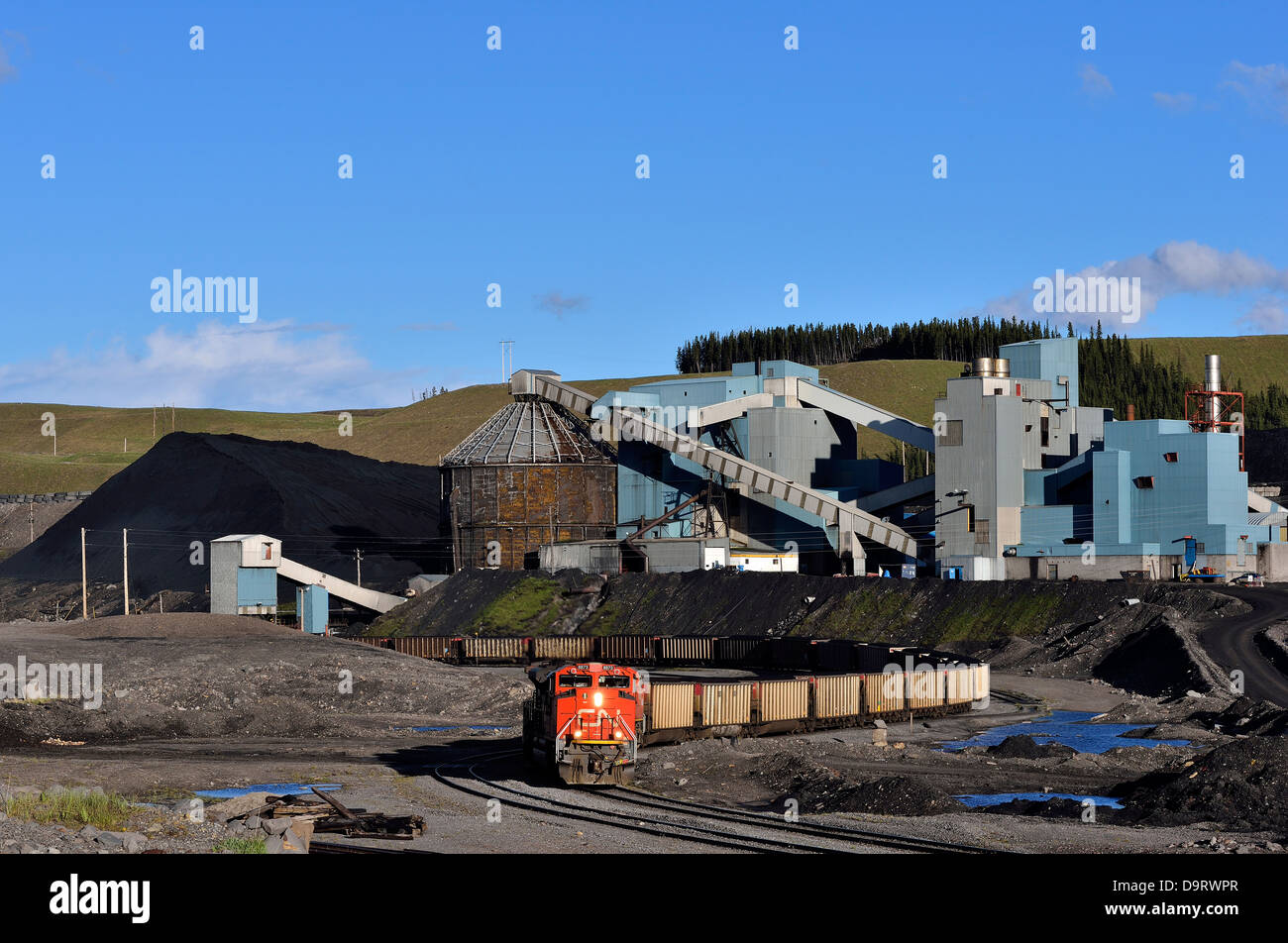 A coal processing plant with piles of coal and a C.N train being loaded ...