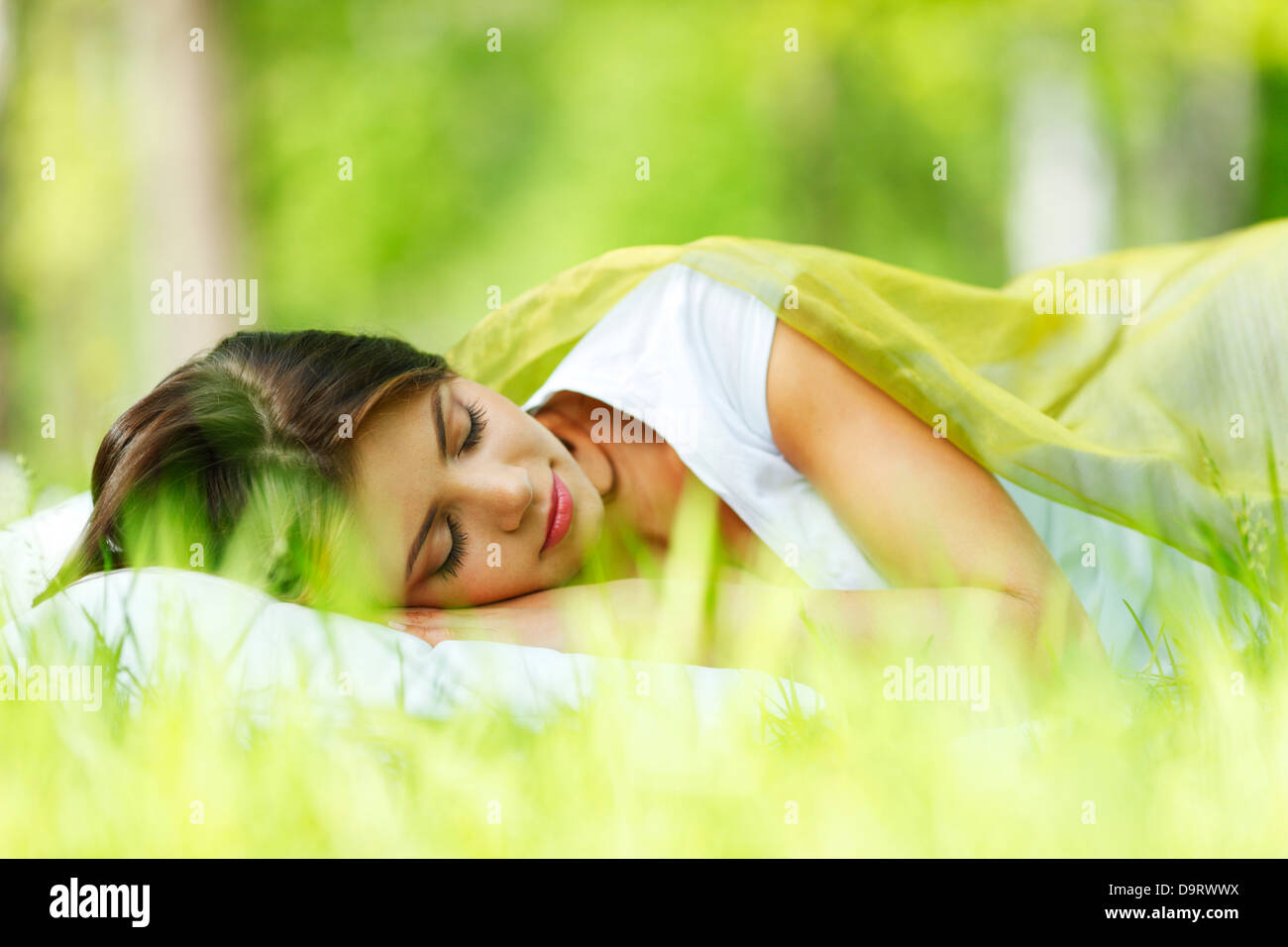 Young woman sleeping on soft pillow in fresh spring grass Stock Photo ...