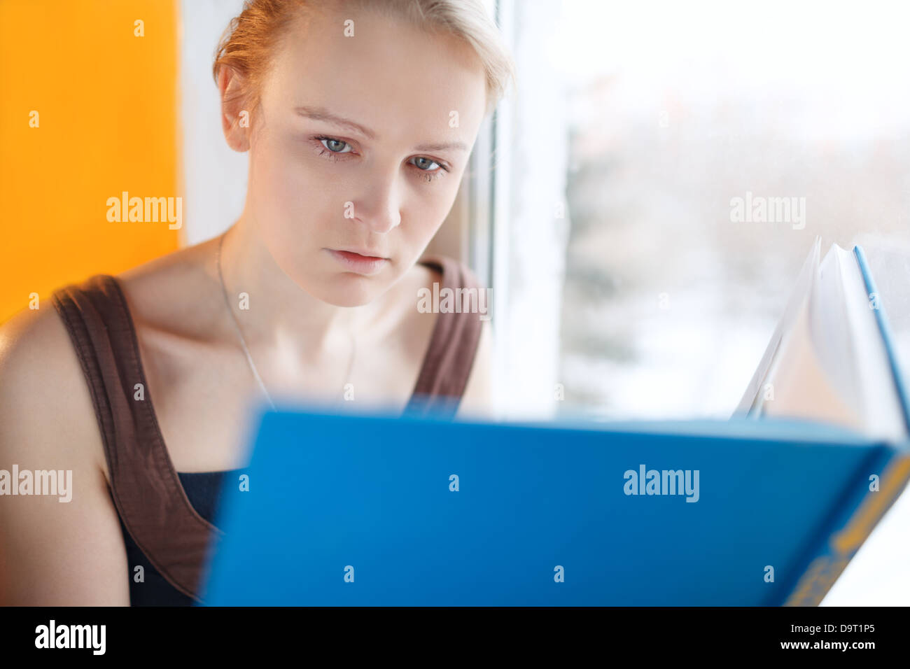 Young woman reading a book with blue cover Stock Photo - Alamy