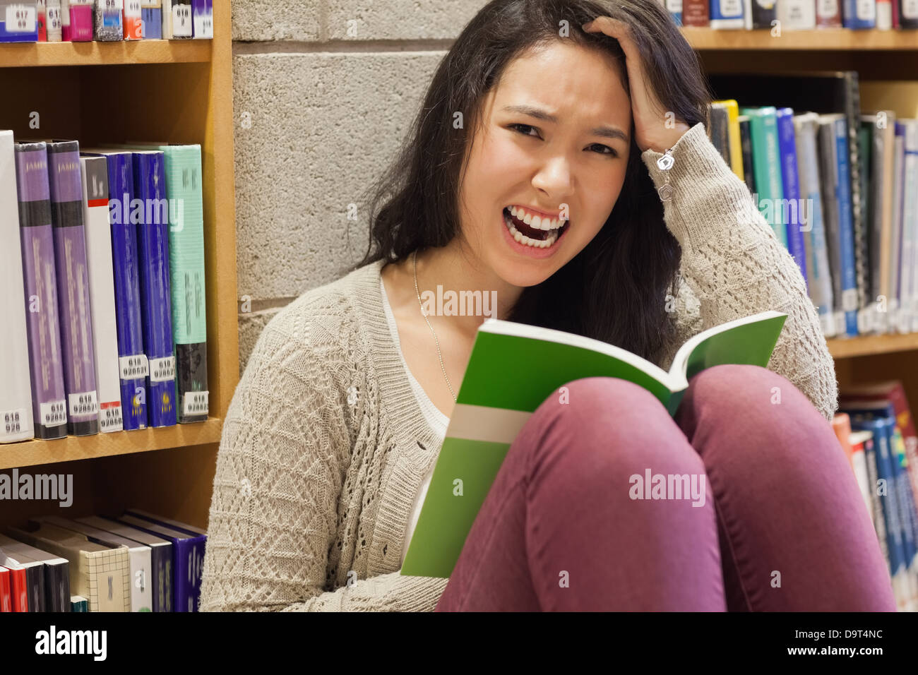 Stressed student reading in a library Stock Photo - Alamy
