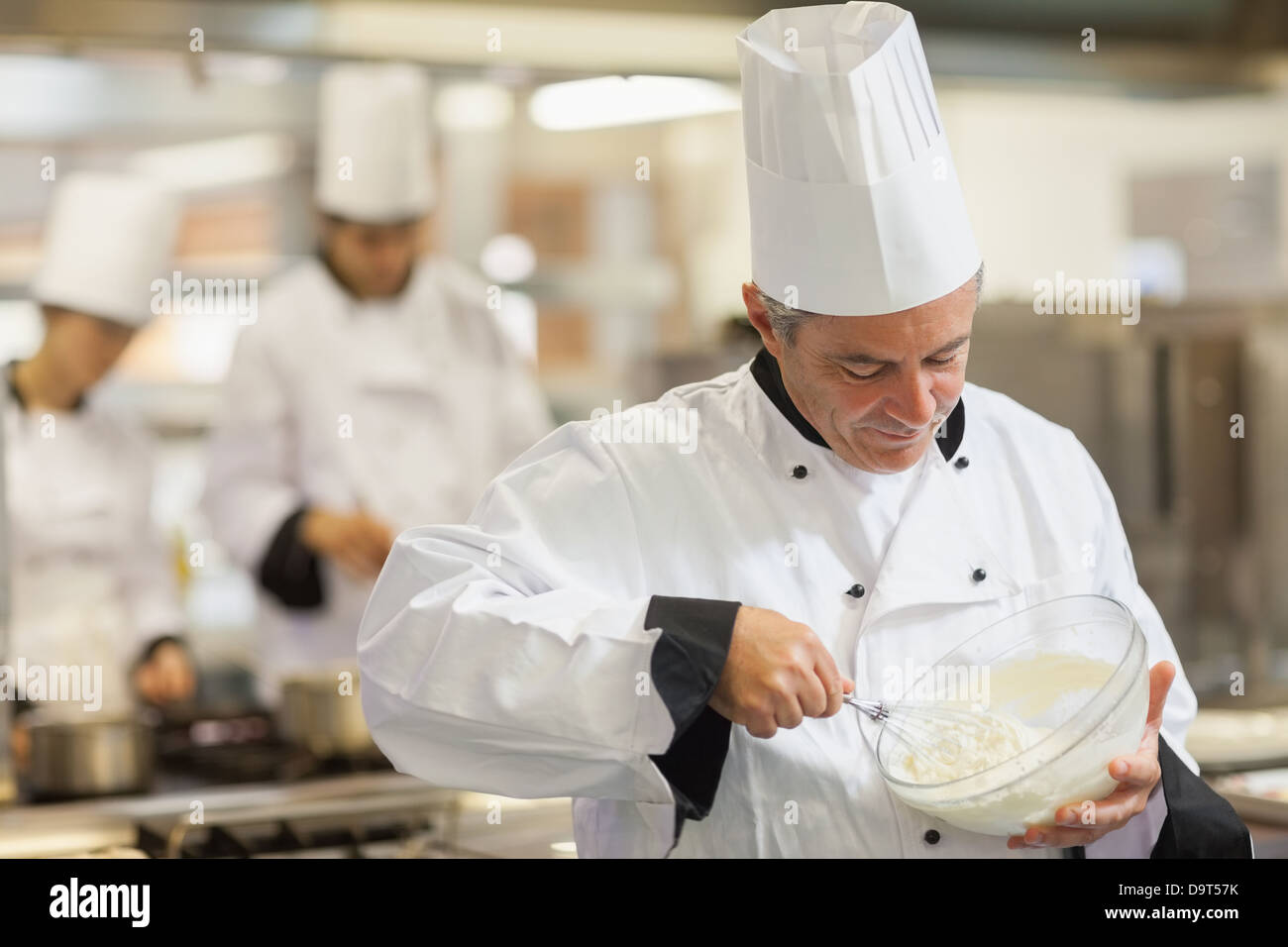 Happy chef whisking cream Stock Photo - Alamy