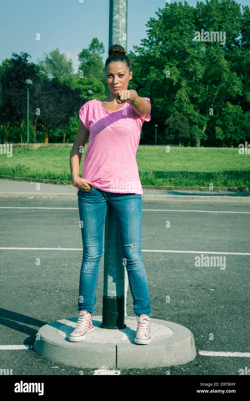 Portrait of a beautiful girl with casual look pointing her finger to ...