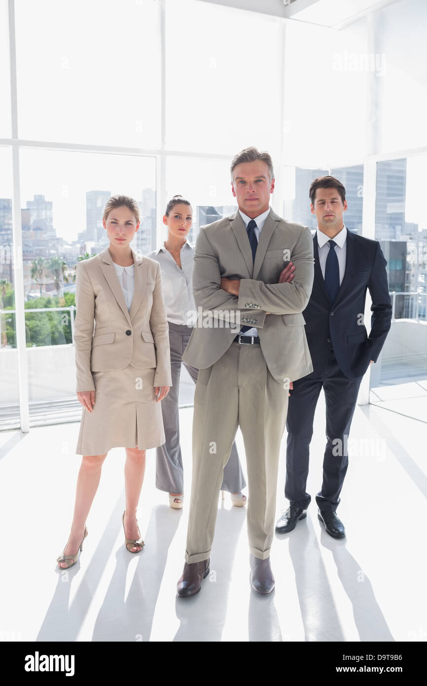 Boss standing with his arms folded with serious colleagues behind Stock ...