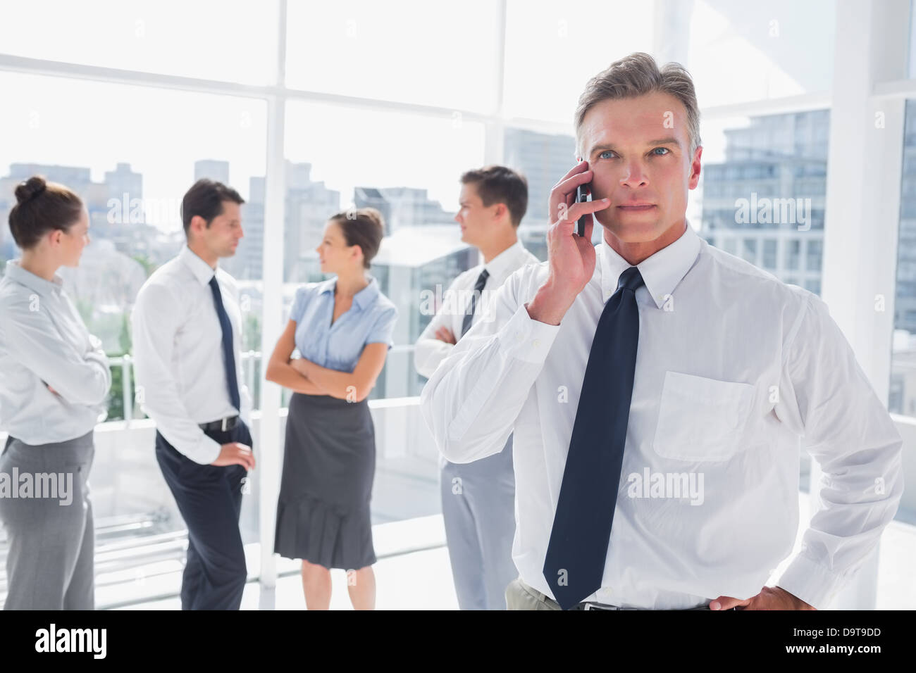 Boss on the phone standing in a modern office Stock Photo - Alamy
