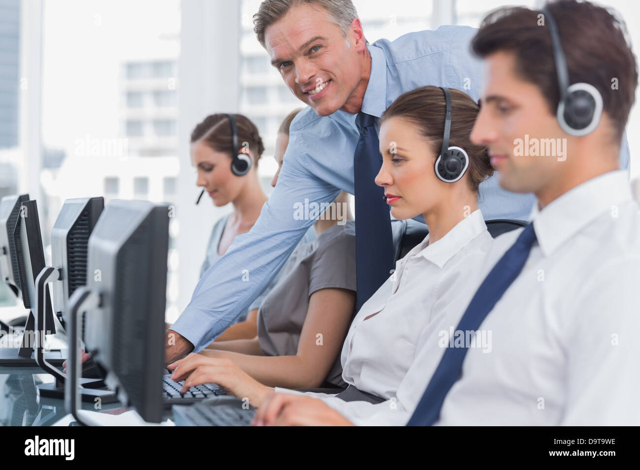 Smiling manager helping call centre employee Stock Photo - Alamy