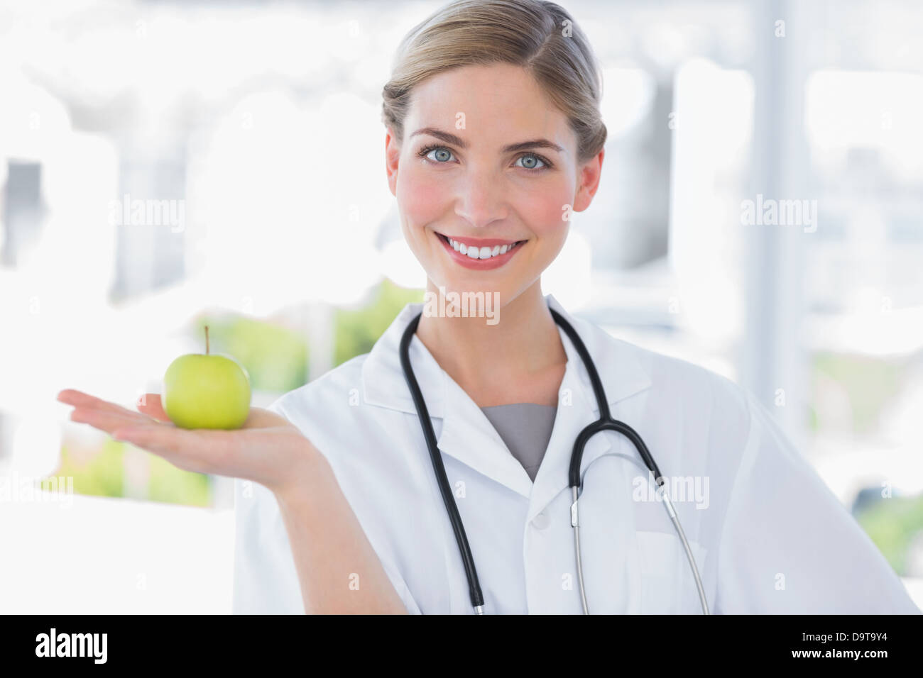 Attractive woman doctor showing an apple Stock Photo - Alamy