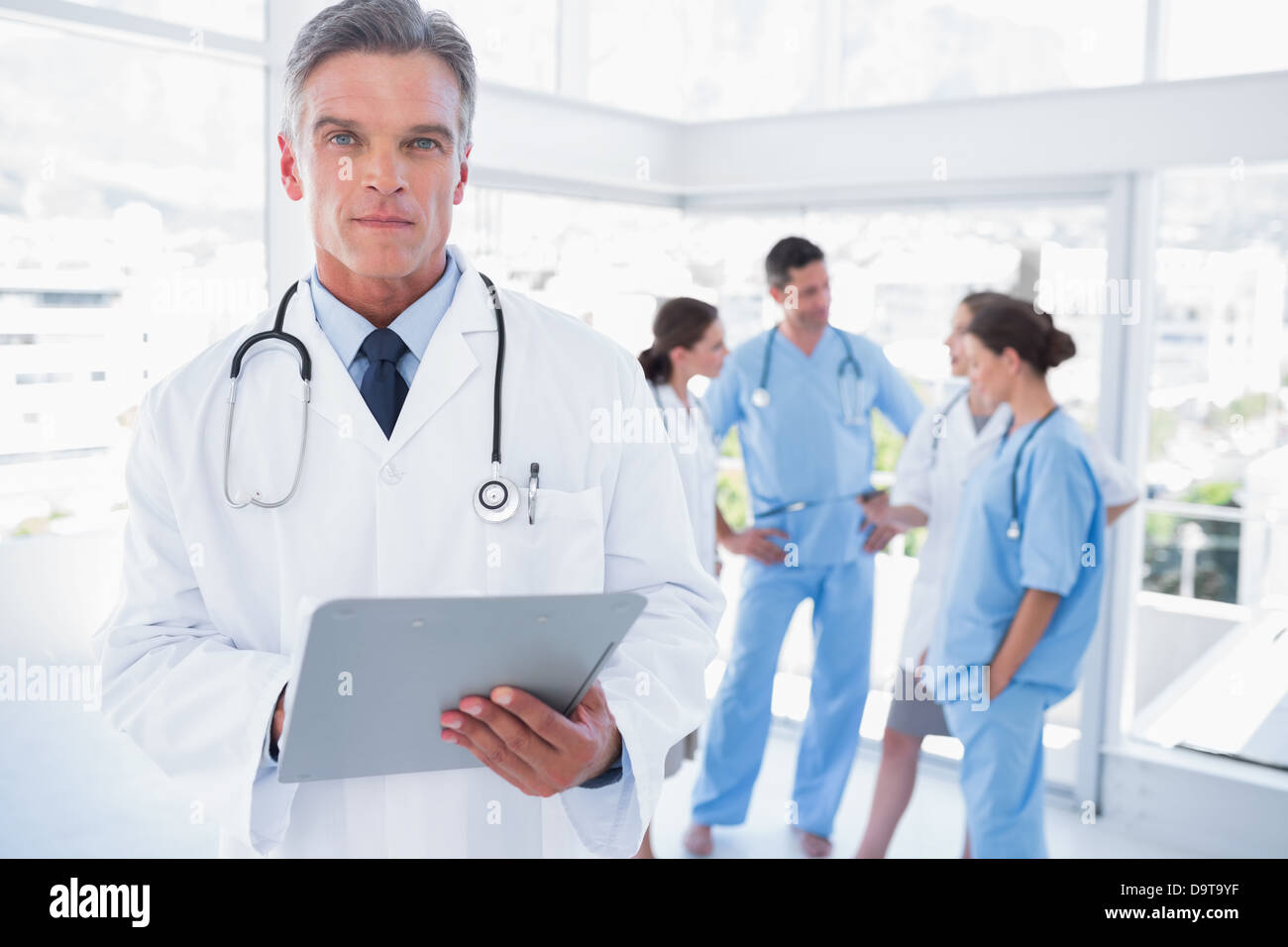 Serious doctor holding clipboard Stock Photo - Alamy