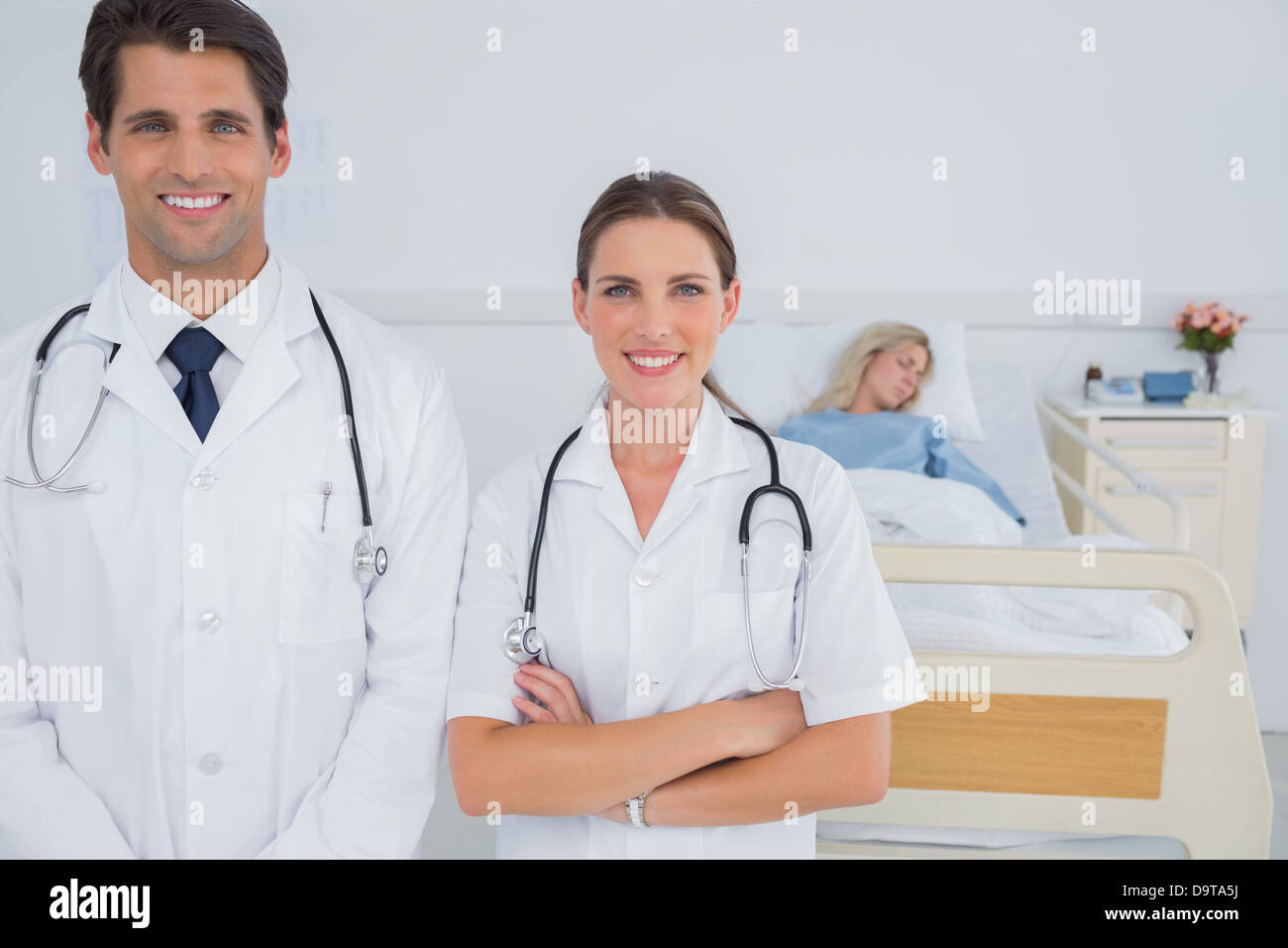Two doctors standing in front of a hospitalized patient Stock Photo - Alamy