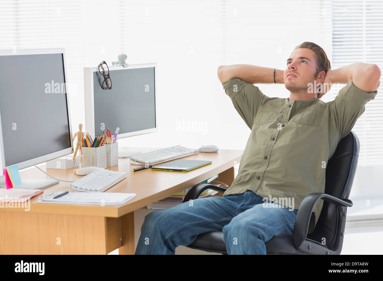 Handsome designer leaning back at his desk Stock Photo - Alamy