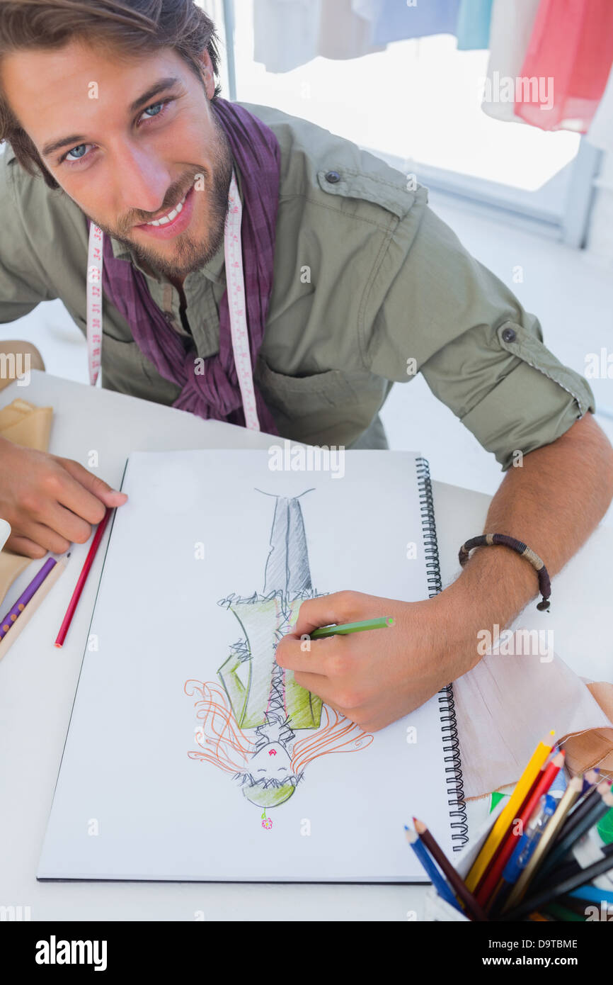 Smiling fashion designer drawing a coat Stock Photo - Alamy