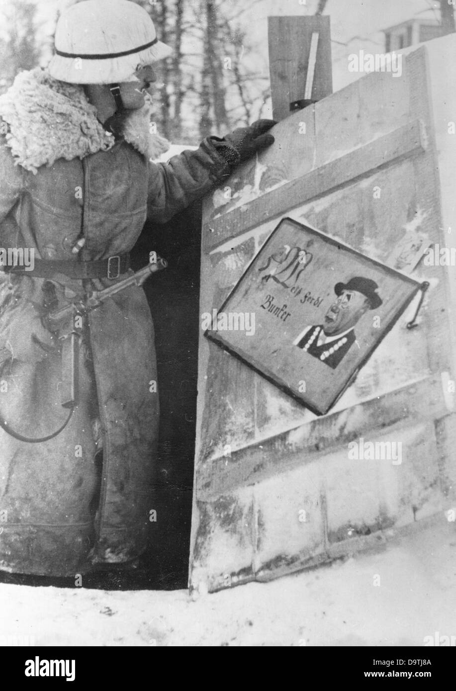 A soldier at the entrance of a bunker, on which a sign is posted ...