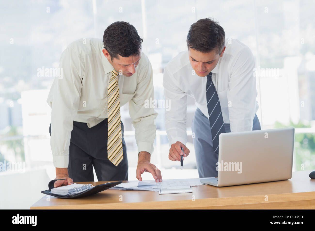 Businessmen working together leaning on desk Stock Photo - Alamy