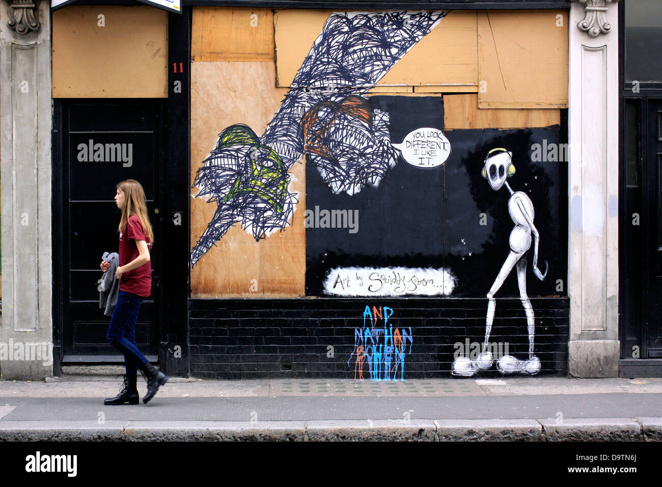 Girl walking past a graffiti covered derelict building in central ...