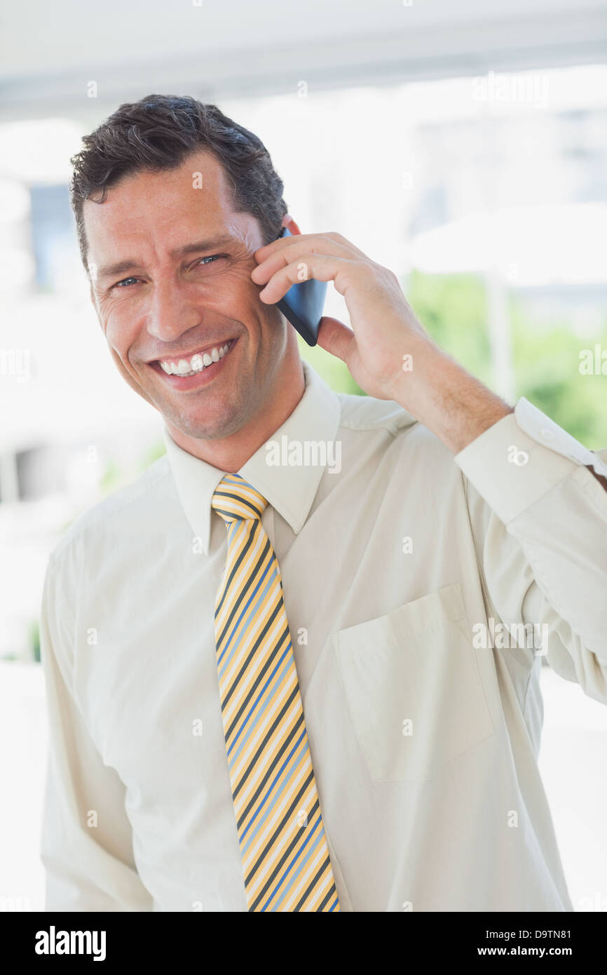 Businessman on the phone smiling at camera Stock Photo - Alamy