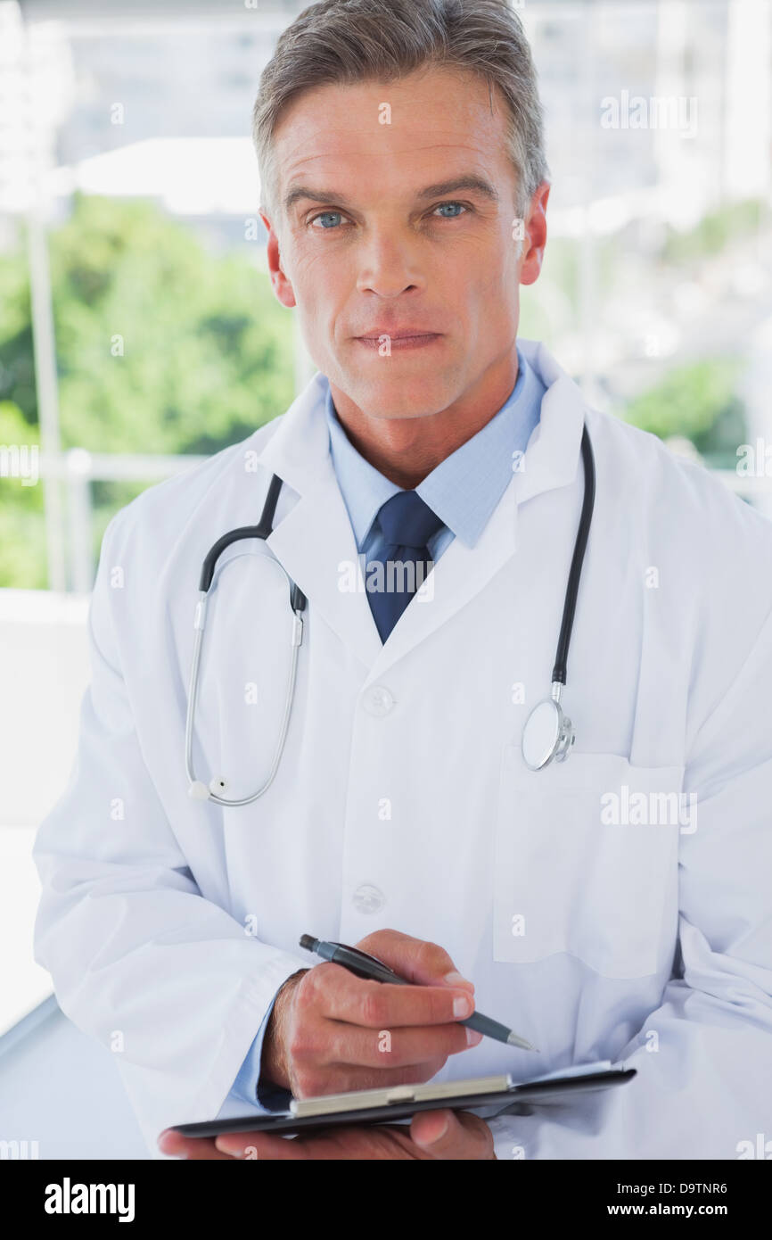 Serious doctor standing with a clipboard Stock Photo - Alamy