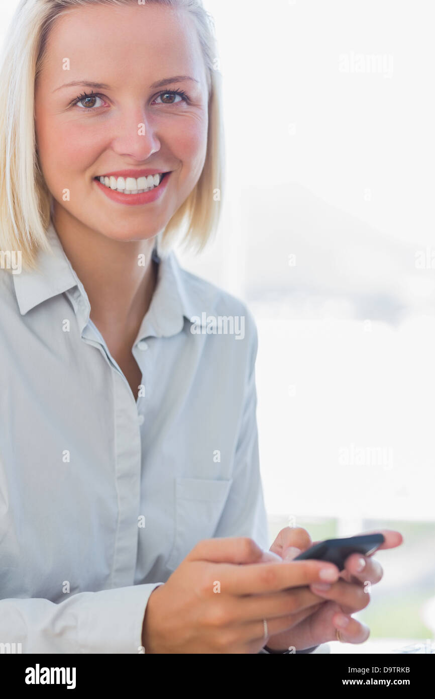 Blonde businesswoman texting and smiling Stock Photo - Alamy