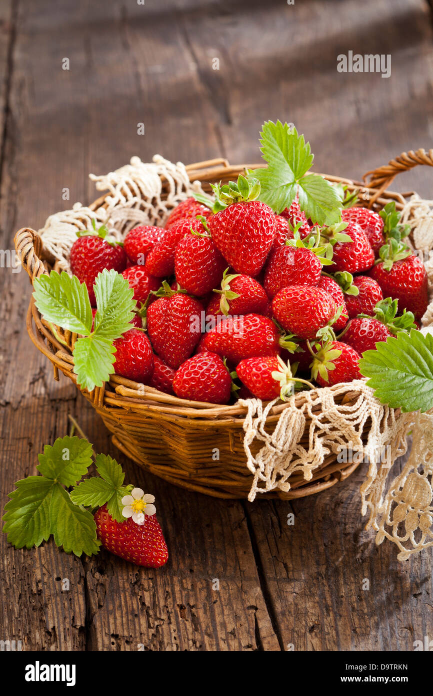 Strawberries in basket on rustic wooden background Stock Photo - Alamy
