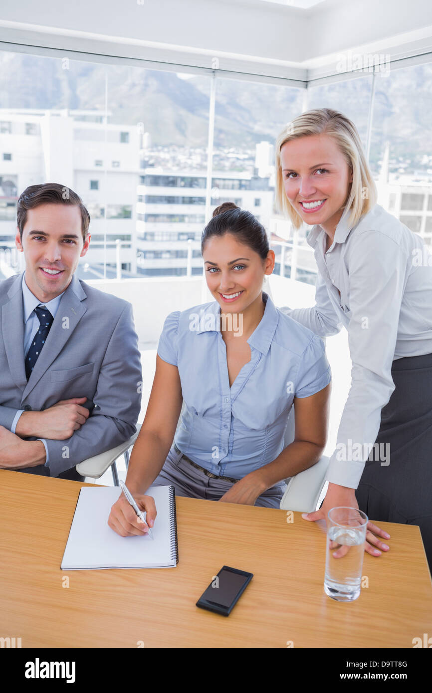 Business people at desk with notepad smiling at camera Stock Photo - Alamy