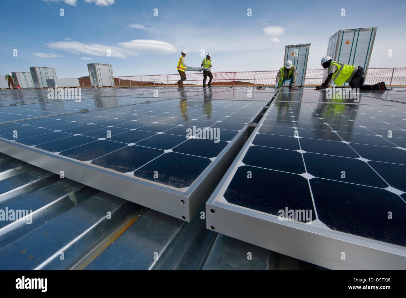 Construction workers install photovoltaic solar electric panels on the ...